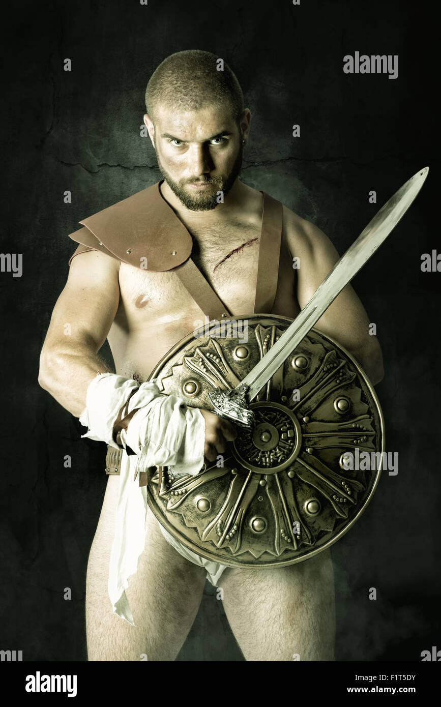 Gladiator posing with shield and sword in a dark background Stock Photo ...