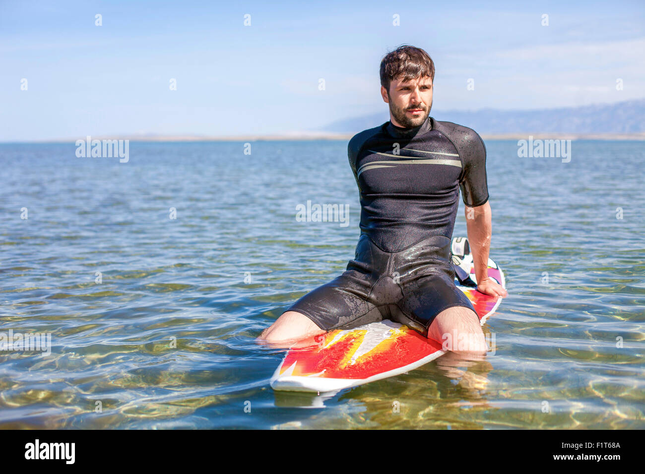 Surfer sitting on surfboard Stock Photo - Alamy