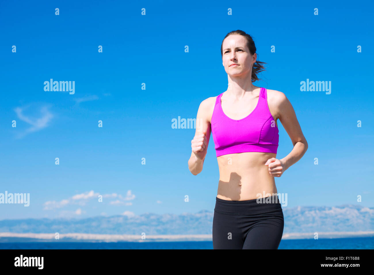 Young woman running on waterfront path Stock Photo - Alamy
