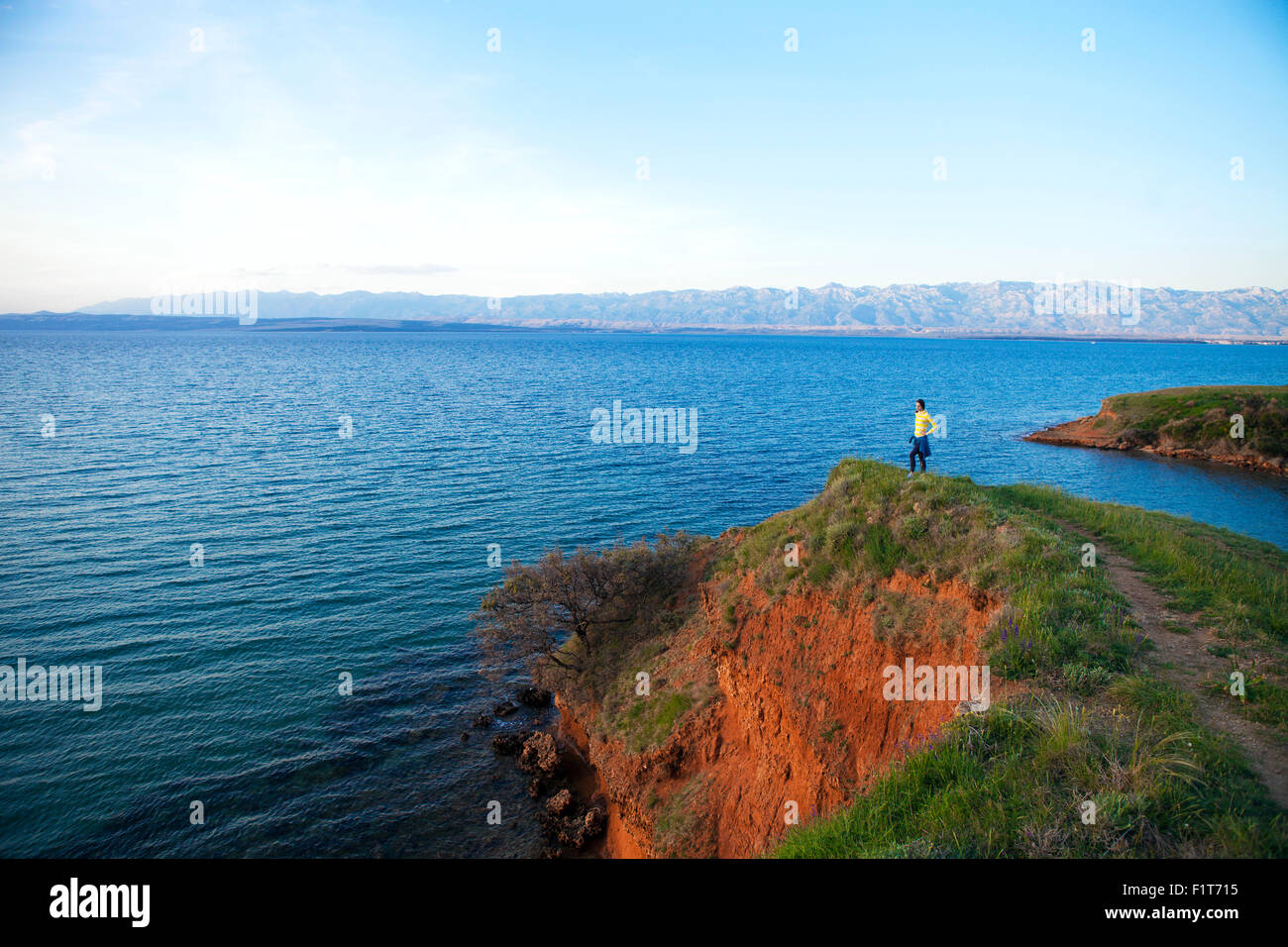 Young woman on cliff looking out at sea Stock Photo - Alamy