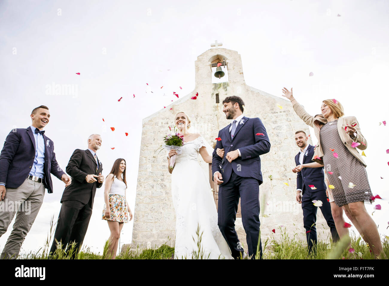 Guests throwing rose petals on bride and groom Stock Photo - Alamy