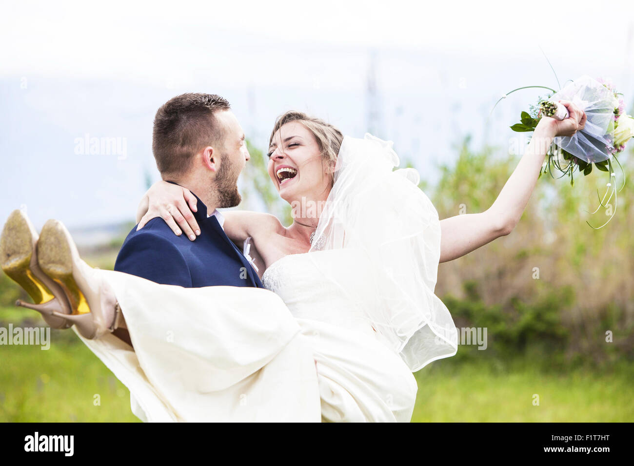 Groom carrying happy bride in the meadow Stock Photo - Alamy