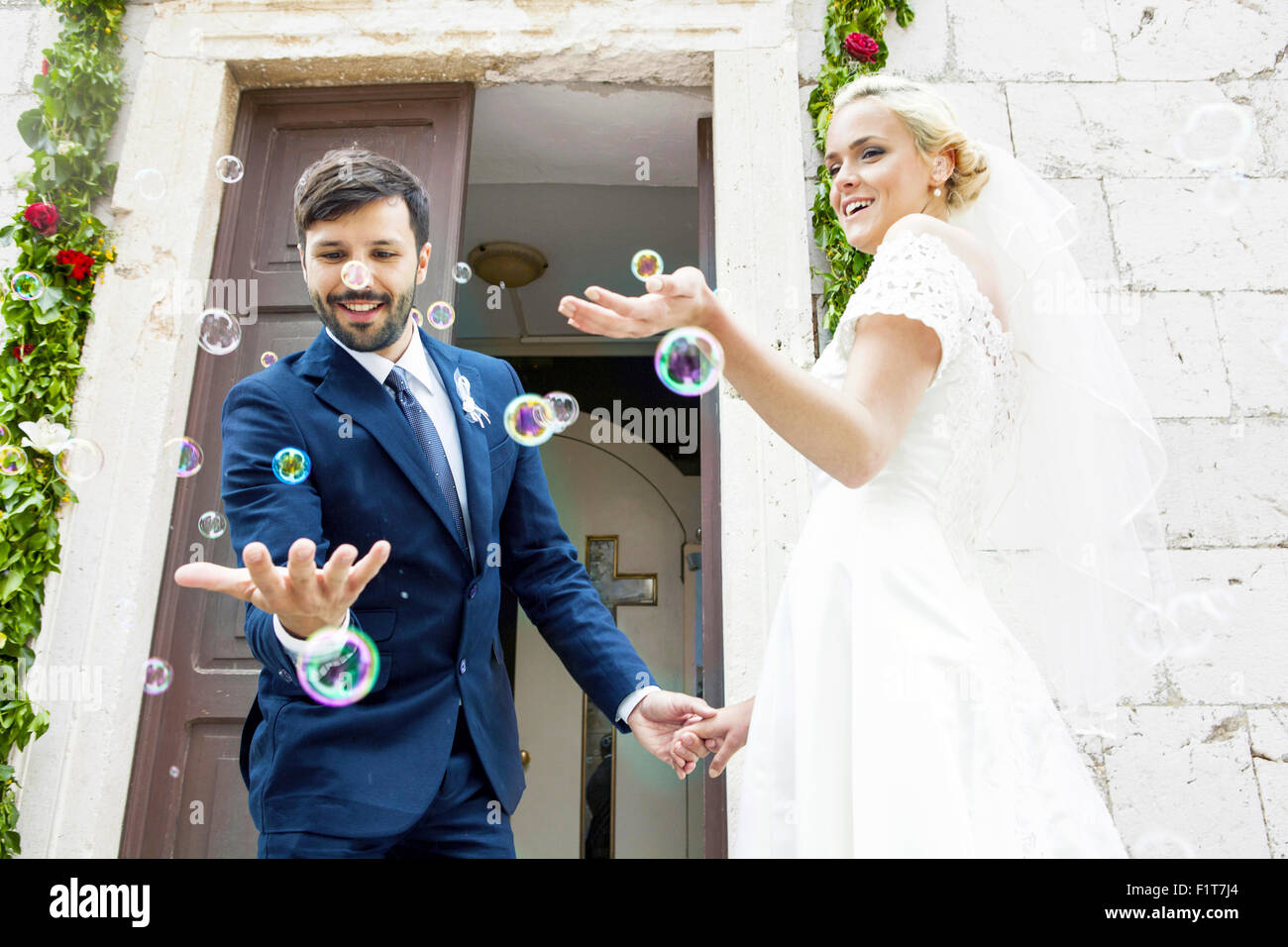 Bride and groom playing with soap bubbles in front of chapel Stock ...