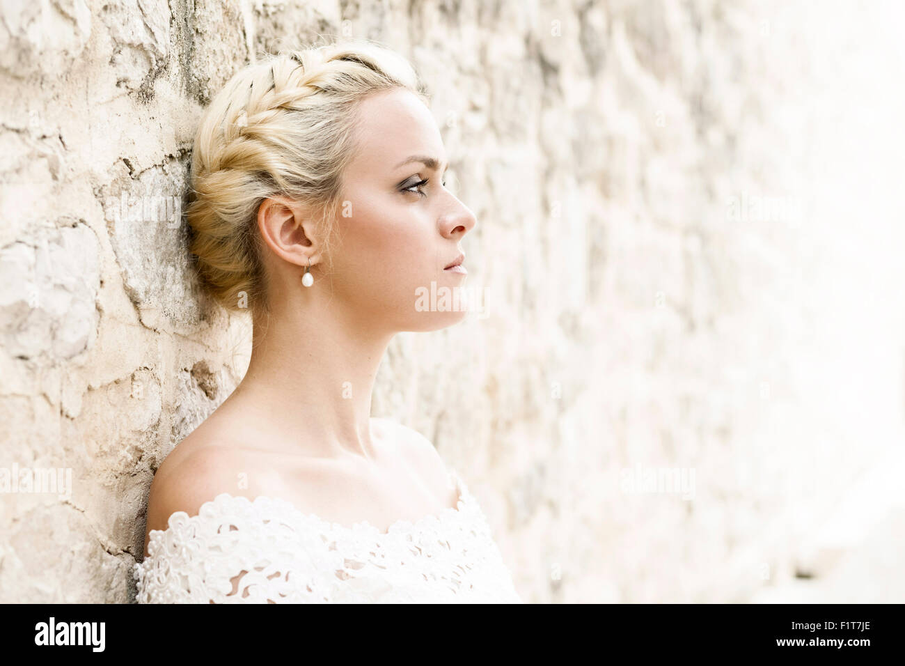 Portrait of bride leaning against wall Stock Photo - Alamy