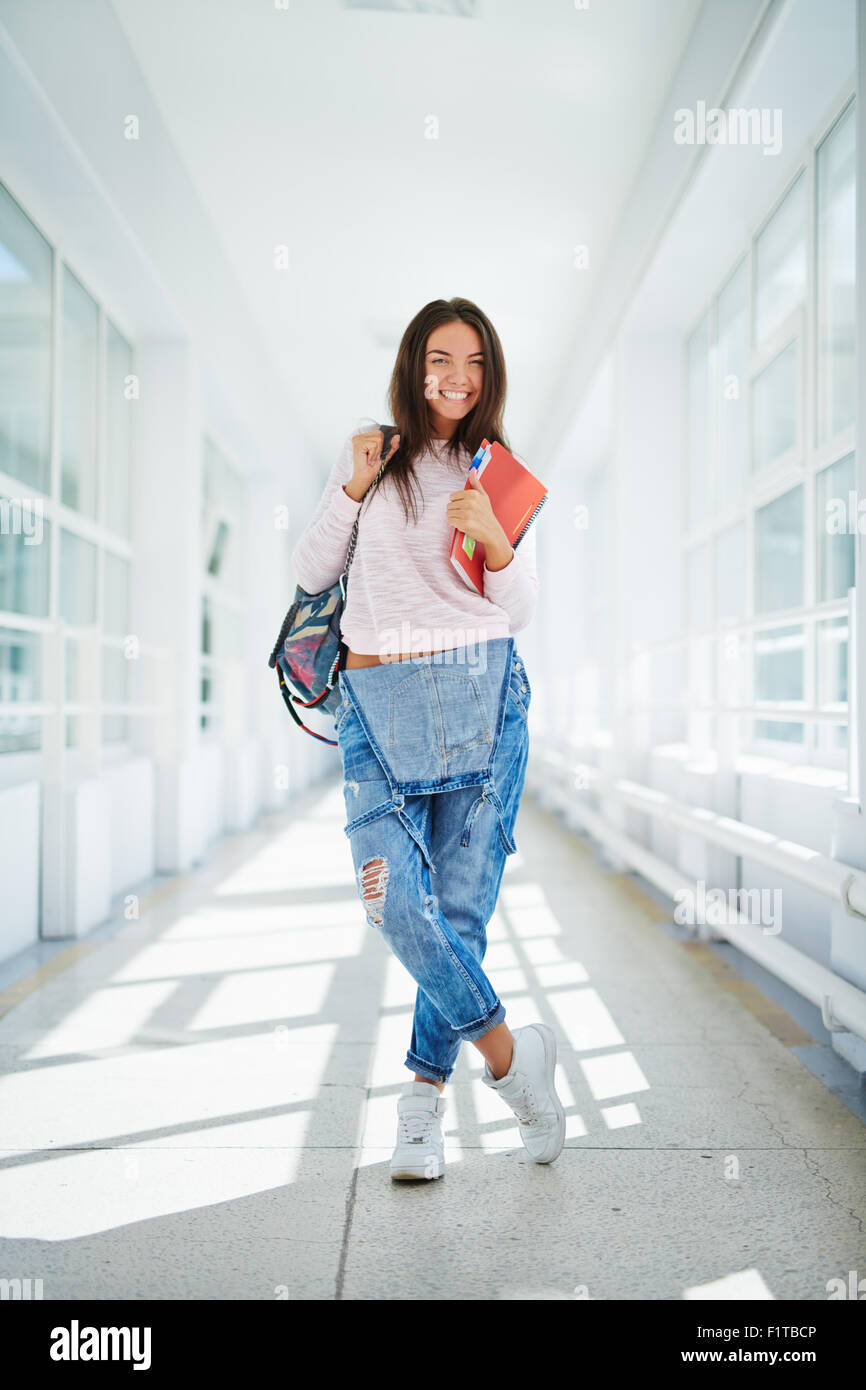 Pretty student with backpack and books standing in college corridor ...