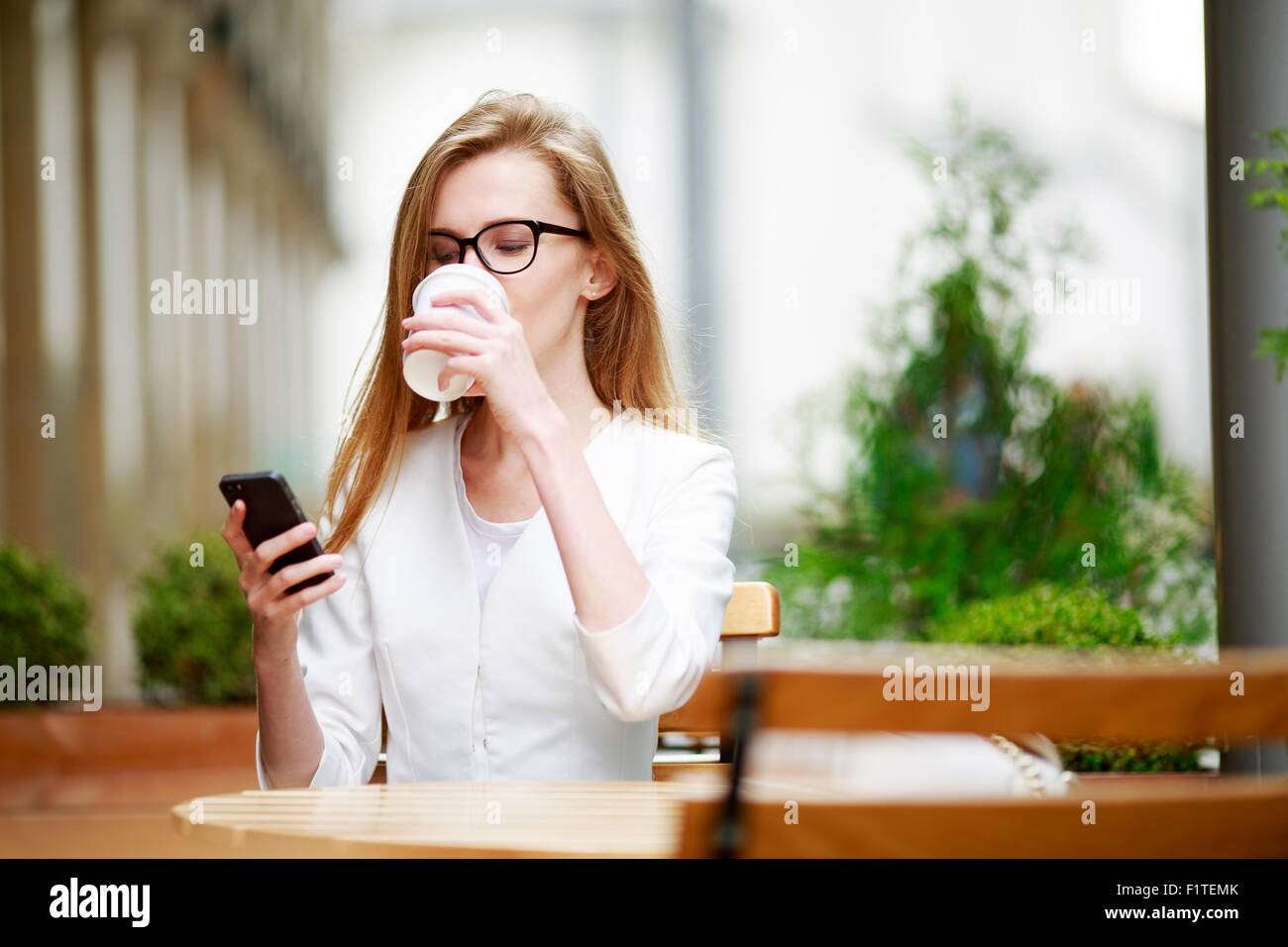 Girl texting on the smart phone in a restaurant terrace with an ...