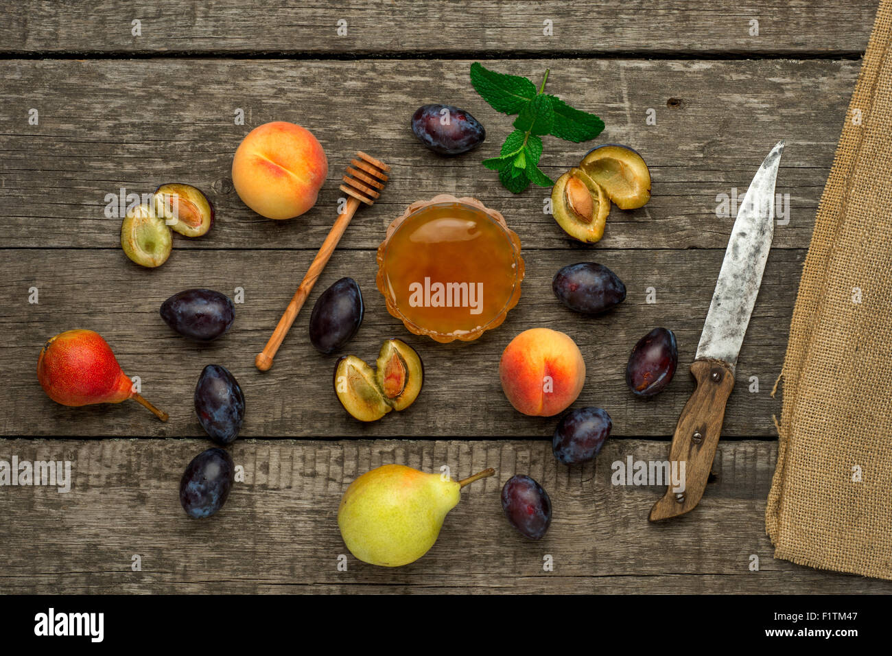 Ripe fruits of peach, plums and pear with honey in a tray on rustic ...