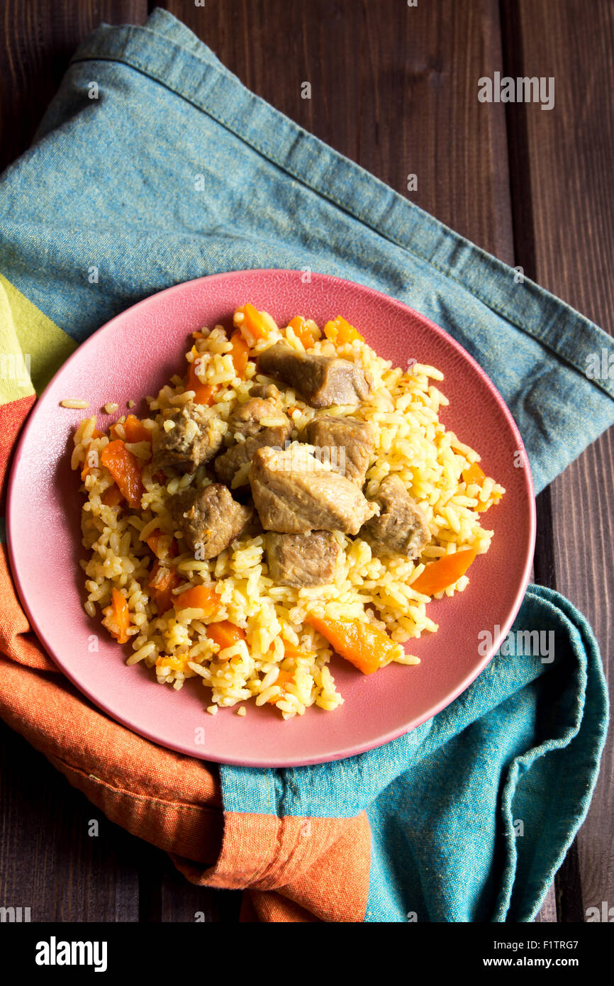 Rice pilaf with lamb meat and vegetables on wooden table and napkin ...