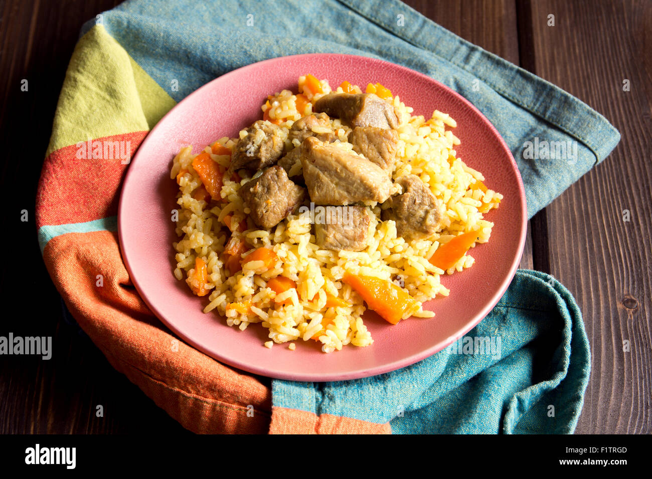 Rice pilaf with lamb meat and vegetables on wooden table and napkin ...