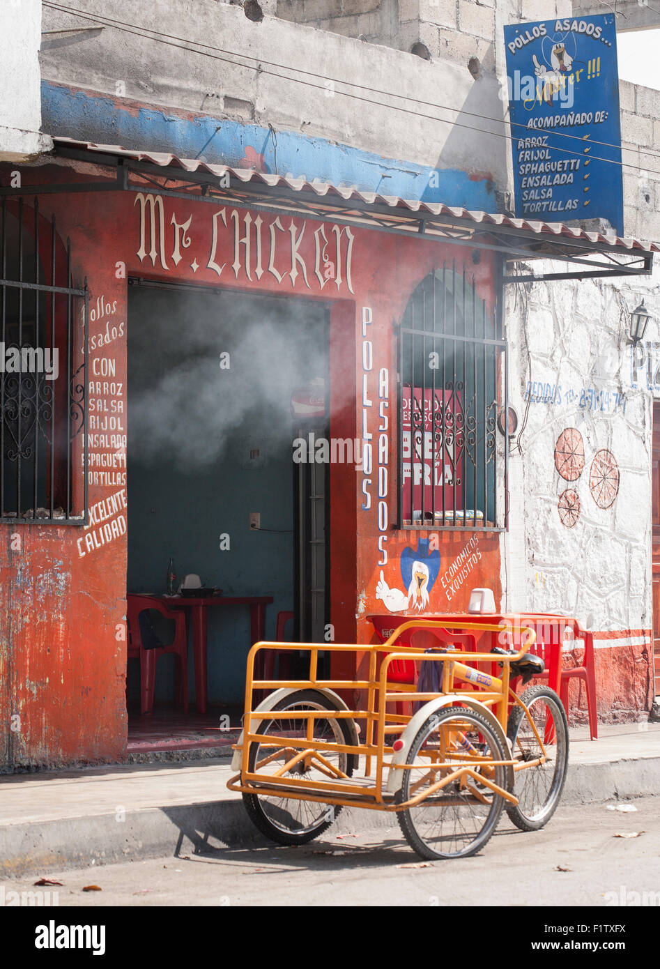 Mister Chicken with bicycle delivery vehicle. A tricycle waits outside ...