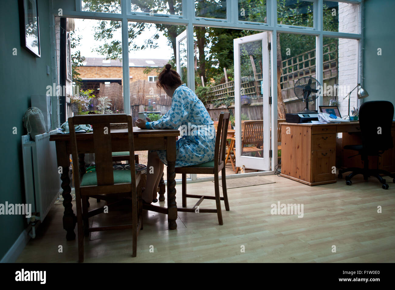 Woman seated at dining table in conservatory Stock Photo - Alamy