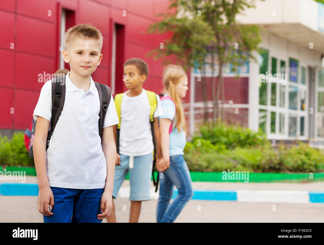 Three kids with rucksacks near school facade Stock Photo - Alamy