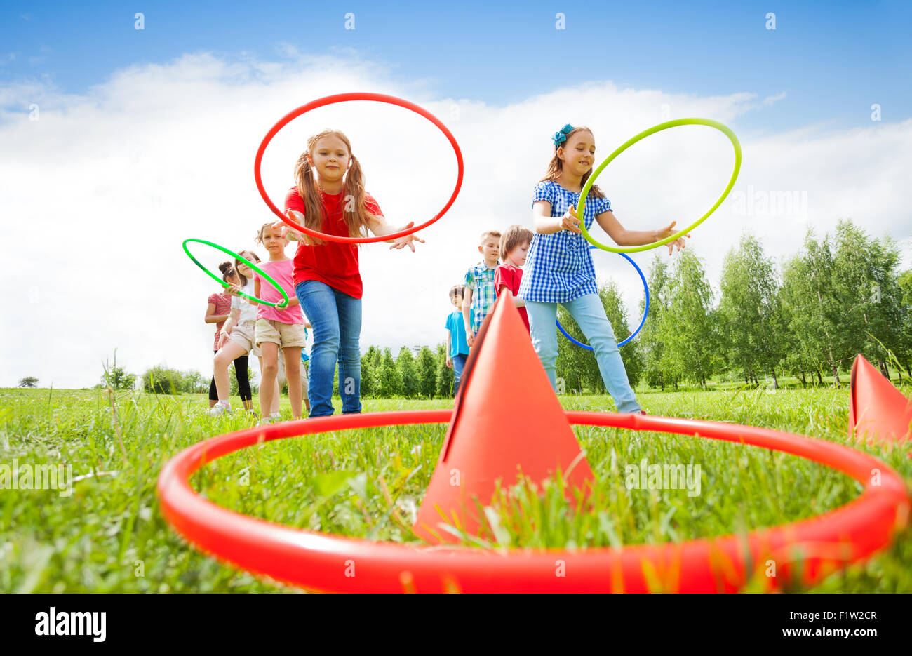 Kids throw colorful hoops on cones while competing Stock Photo - Alamy