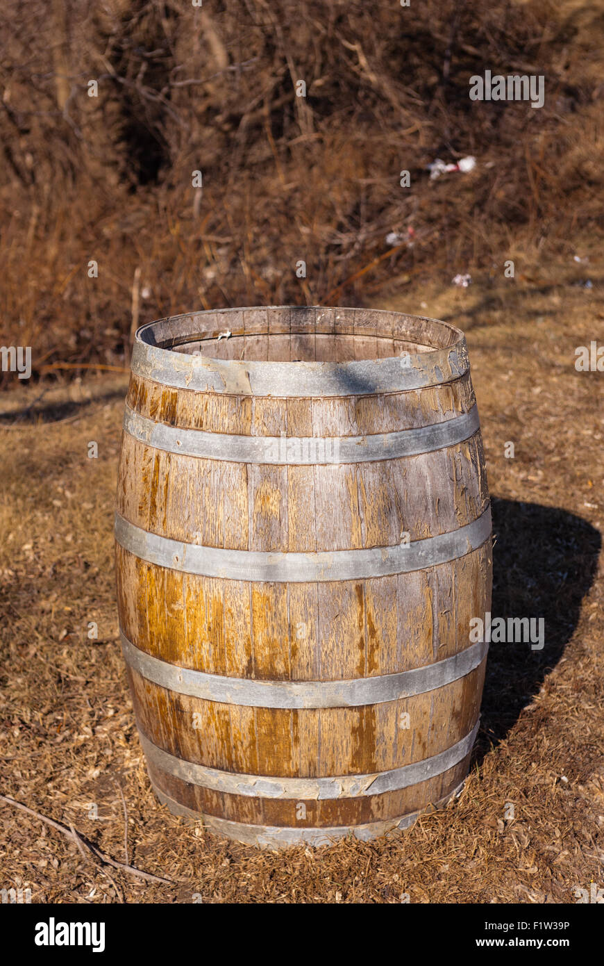 One worn wooden reinforced barrel, illuminated by sun and casting ...