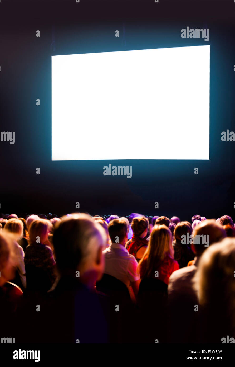 Crowd audience in dark looking at bright screen Stock Photo - Alamy