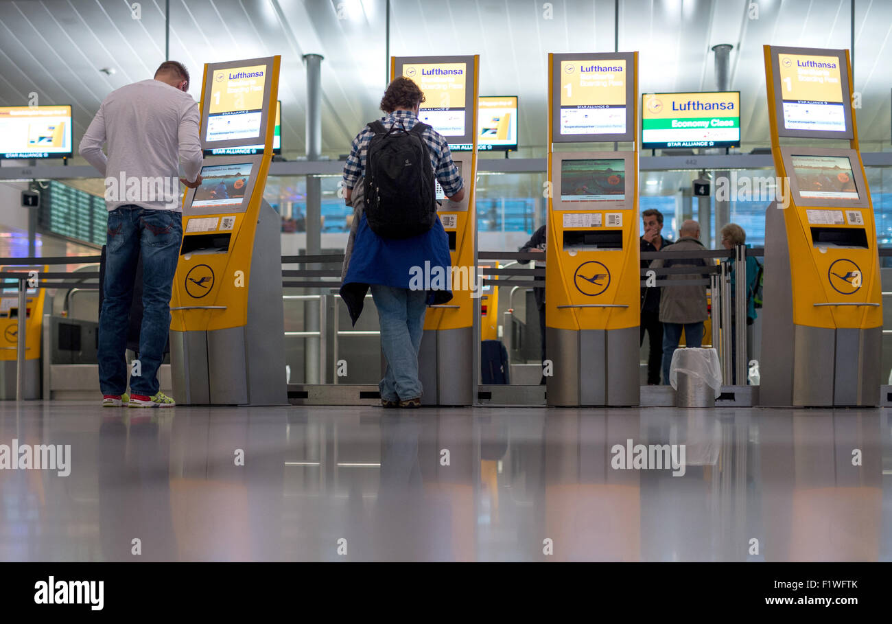 A man and a woman stand in front of Lufthansa self-check-in counters at ...