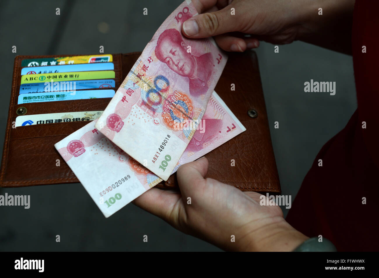 Shanghai, China. 30th Aug, 2015. A woman holds Chinese yuan banknotes ...
