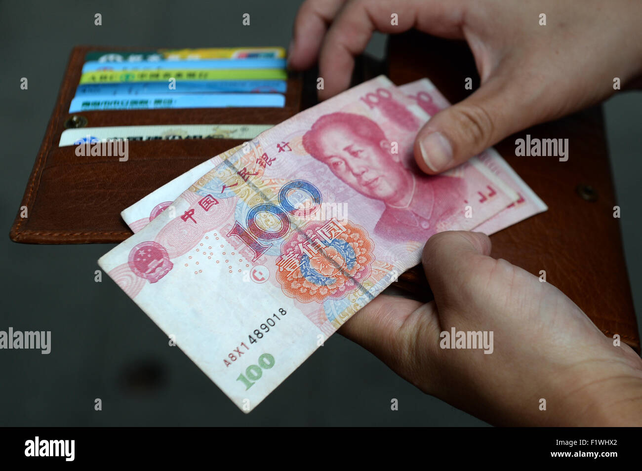 Shanghai, China. 30th Aug, 2015. A woman holds Chinese yuan banknotes ...