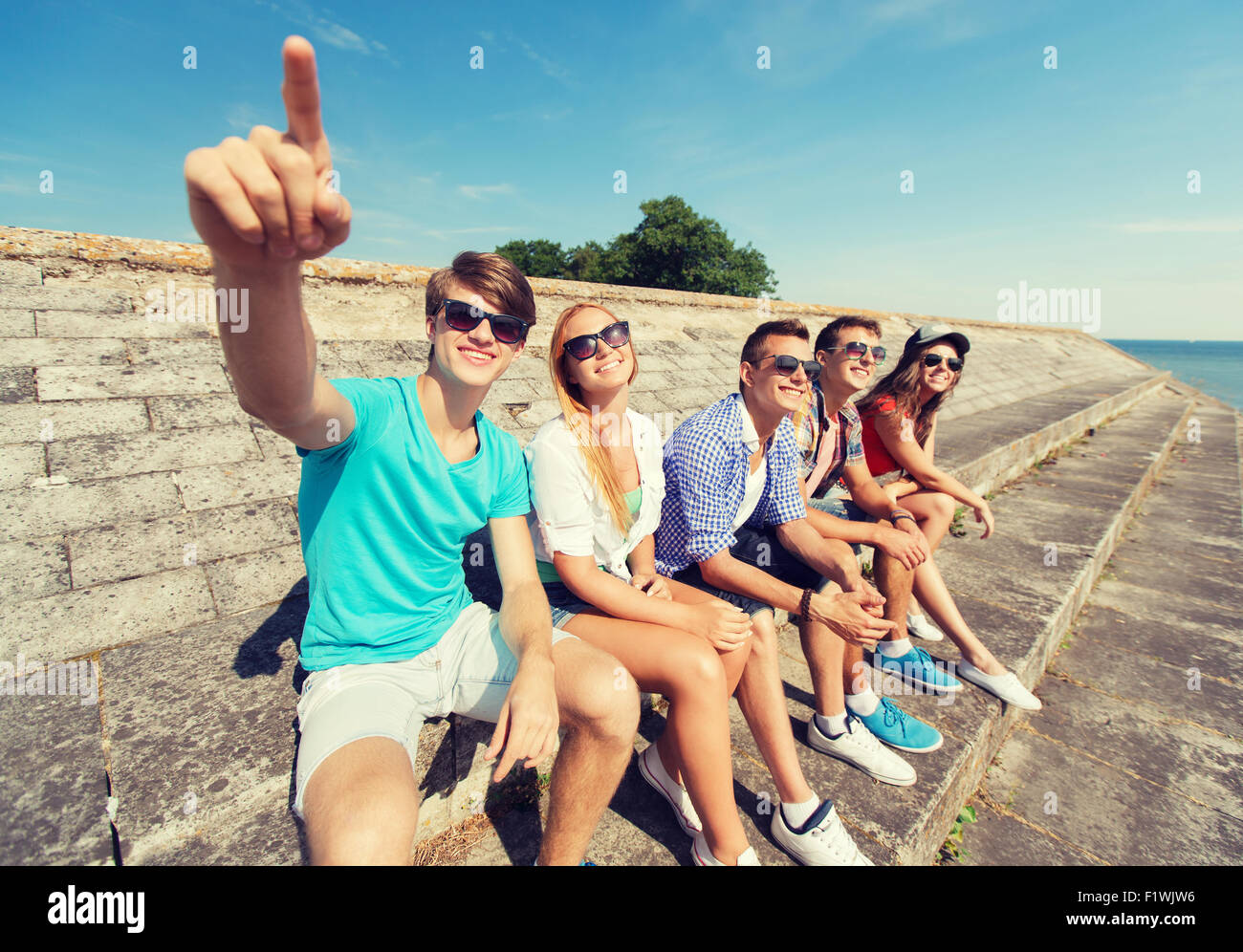 group of smiling friends sitting on city street Stock Photo - Alamy