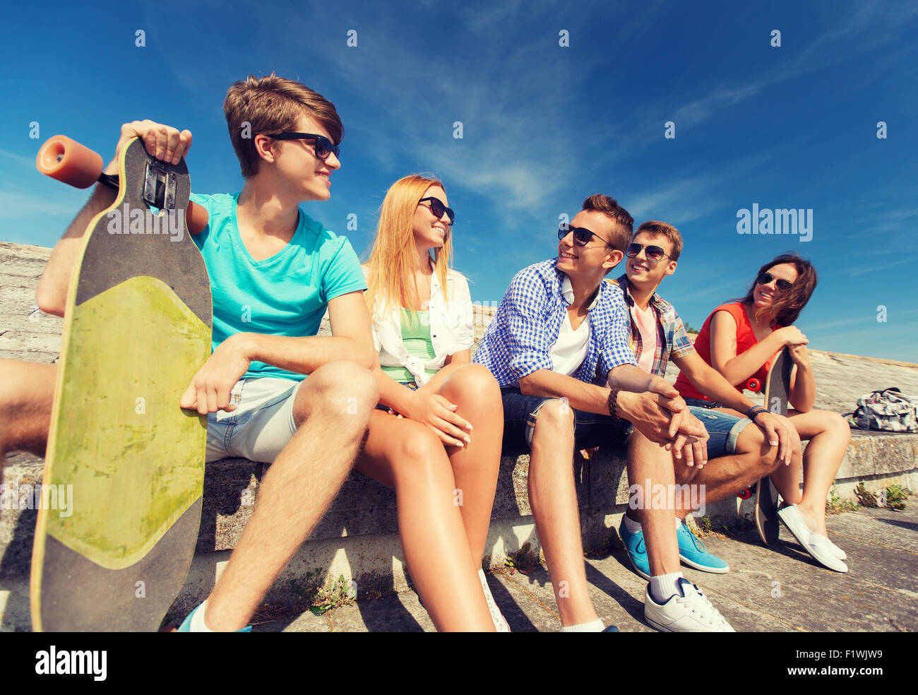 group of smiling friends sitting on city street Stock Photo - Alamy