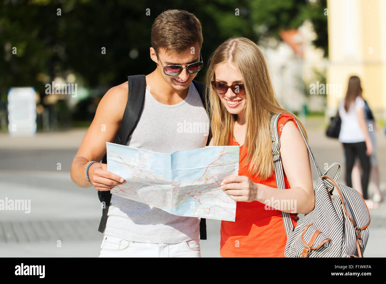 smiling couple with map and backpack in city Stock Photo - Alamy