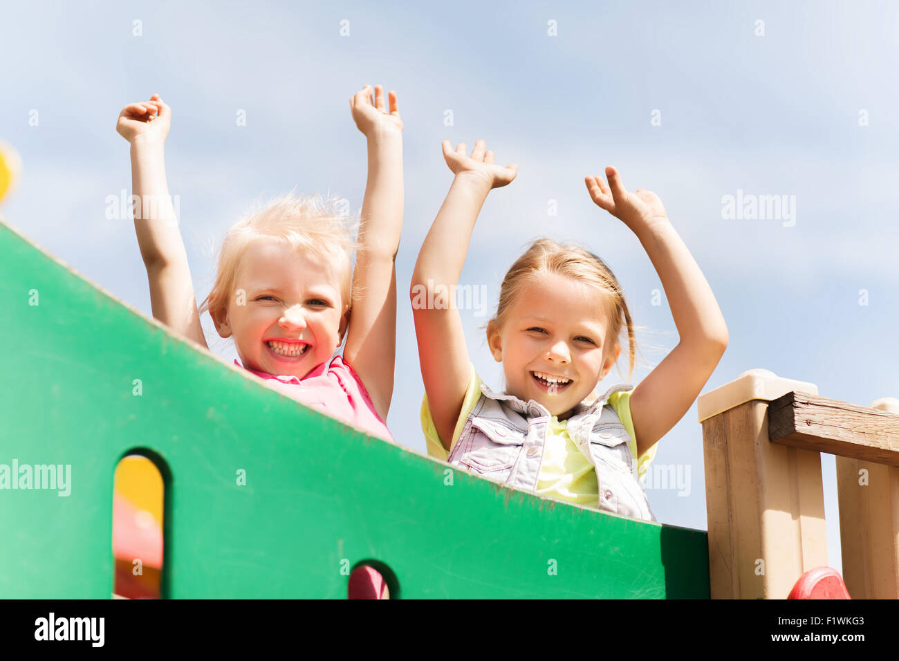 happy girls waving hands on children playground Stock Photo - Alamy