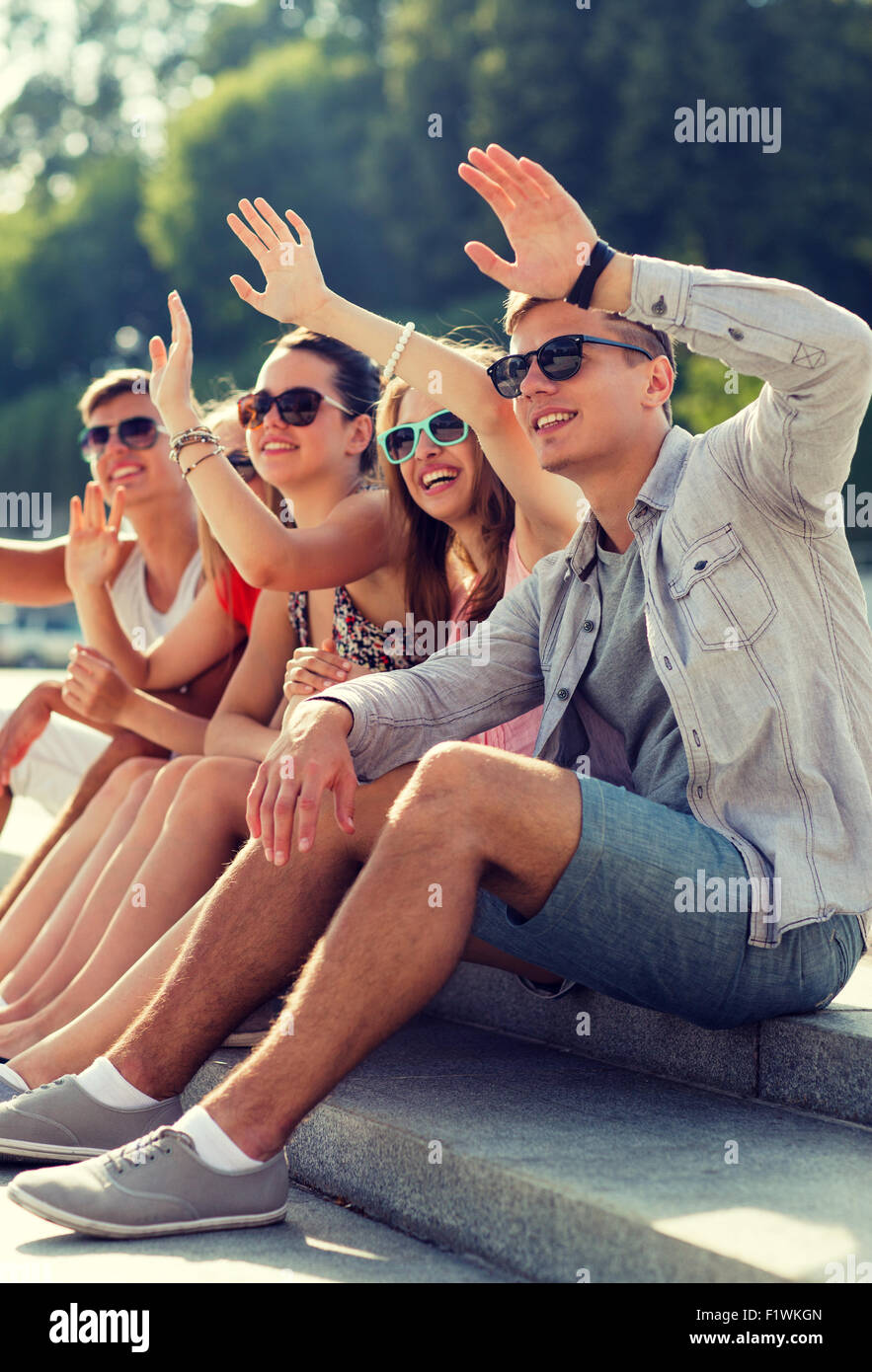 group of smiling friends sitting on city street Stock Photo - Alamy