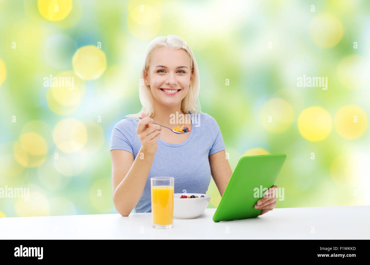 smiling woman with tablet pc eating breakfast Stock Photo - Alamy