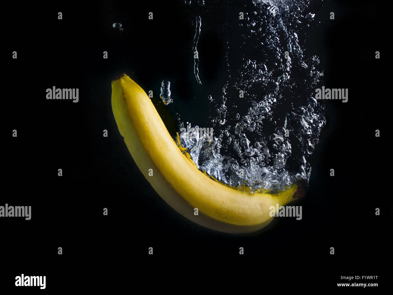 Banana falling into the water with splashes and bubbles. High speed ...