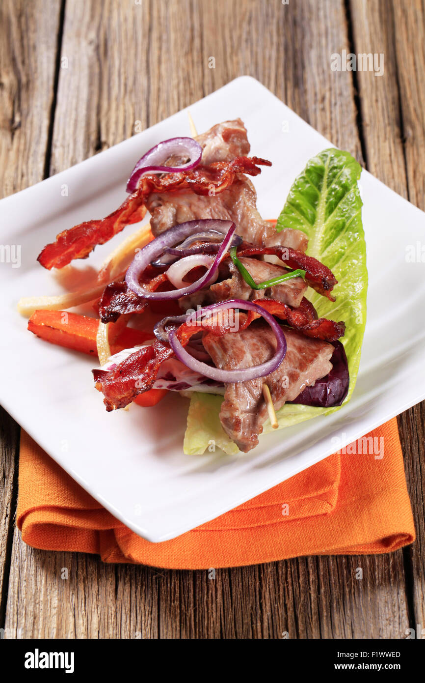 Meat skewer with crispy rashers of bacon and vegetables Stock Photo - Alamy