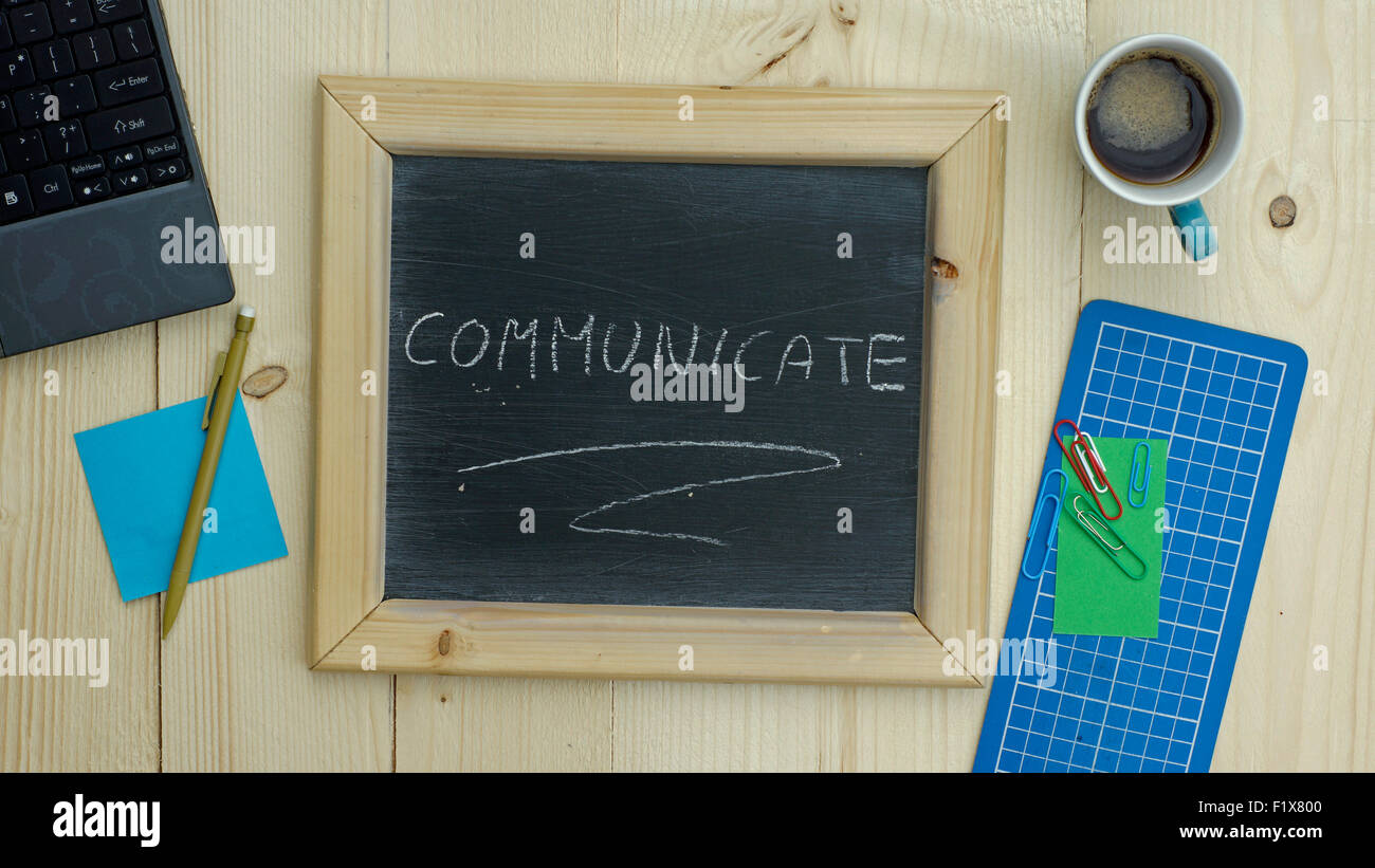 Communicate written on a chalkboard at the office Stock Photo - Alamy