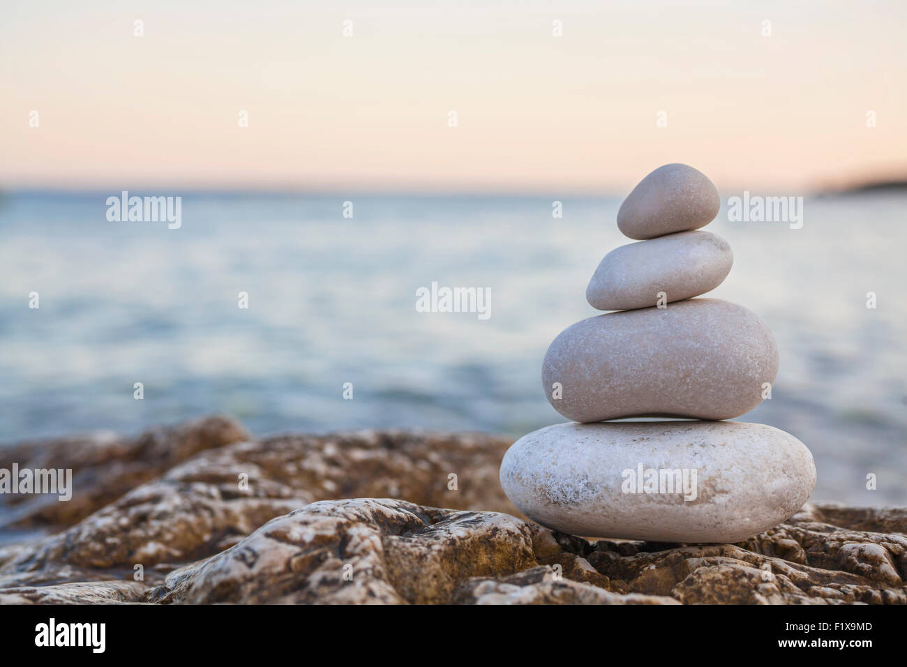 Tower of stones piles on top of a rock on a tranquil deserted beach at ...