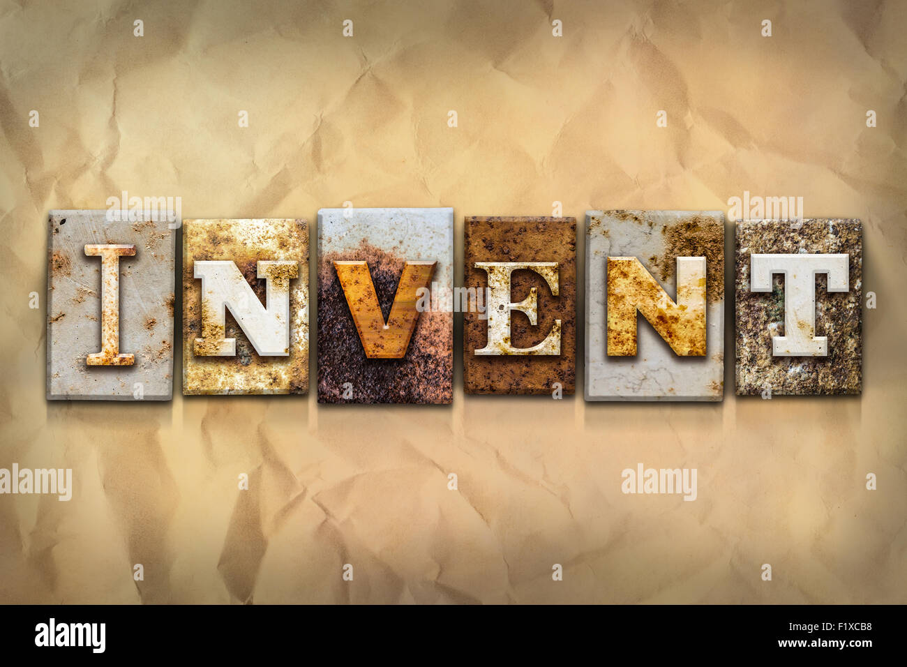 The word "INVENT" written in rusty metal letterpress type on a crumbled ...