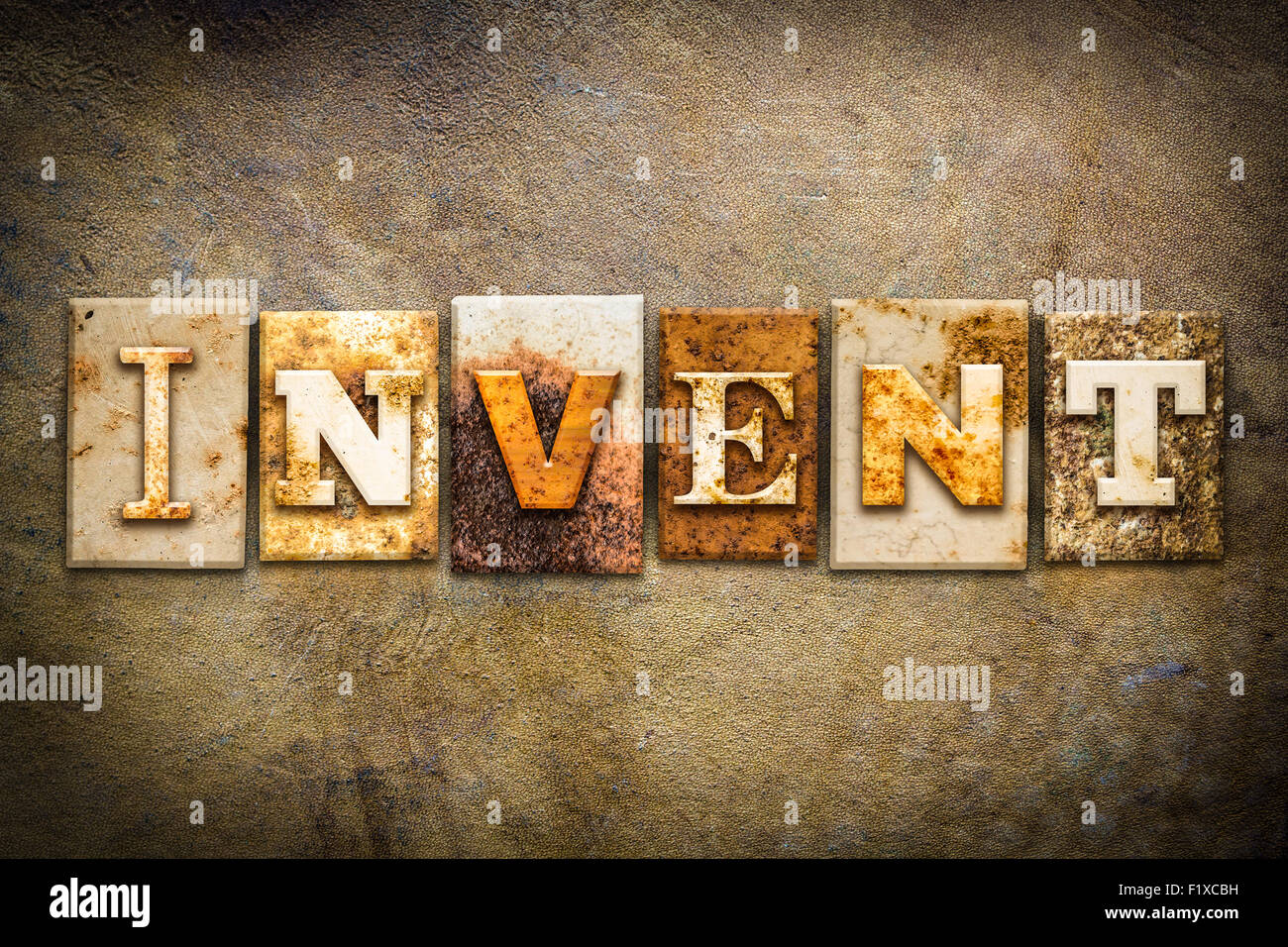 The word "INVENT" written in rusty metal letterpress type on an old ...