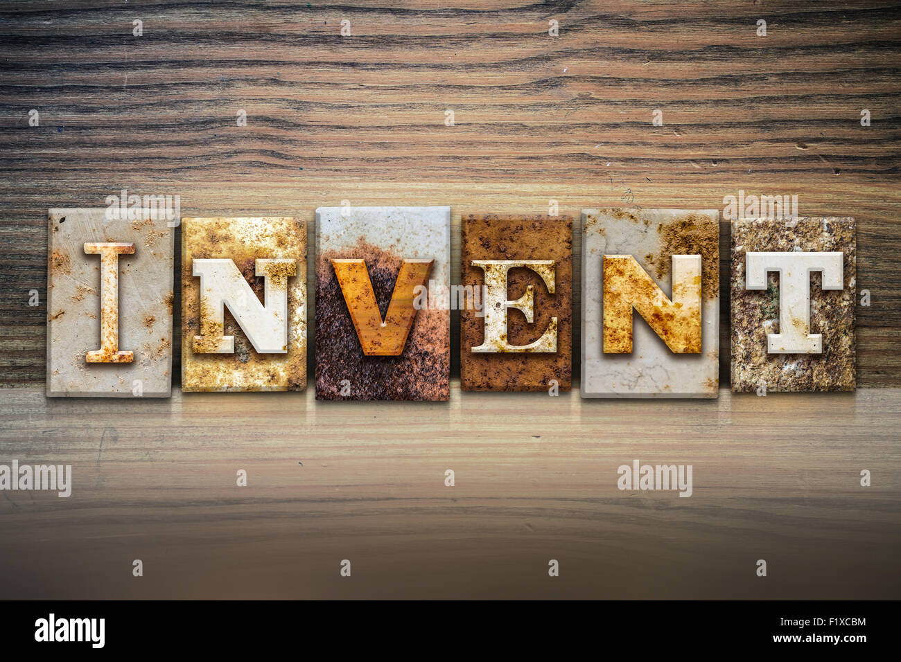 The word "INVENT" written in rusty metal letterpress type sitting on a ...