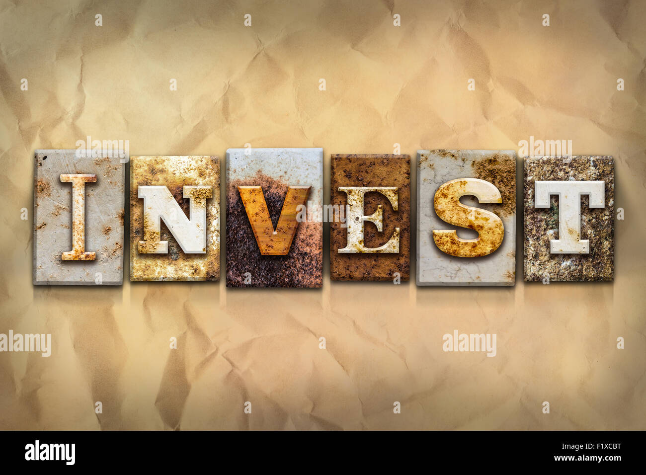 The word "INVEST" written in rusty metal letterpress type on a crumbled ...