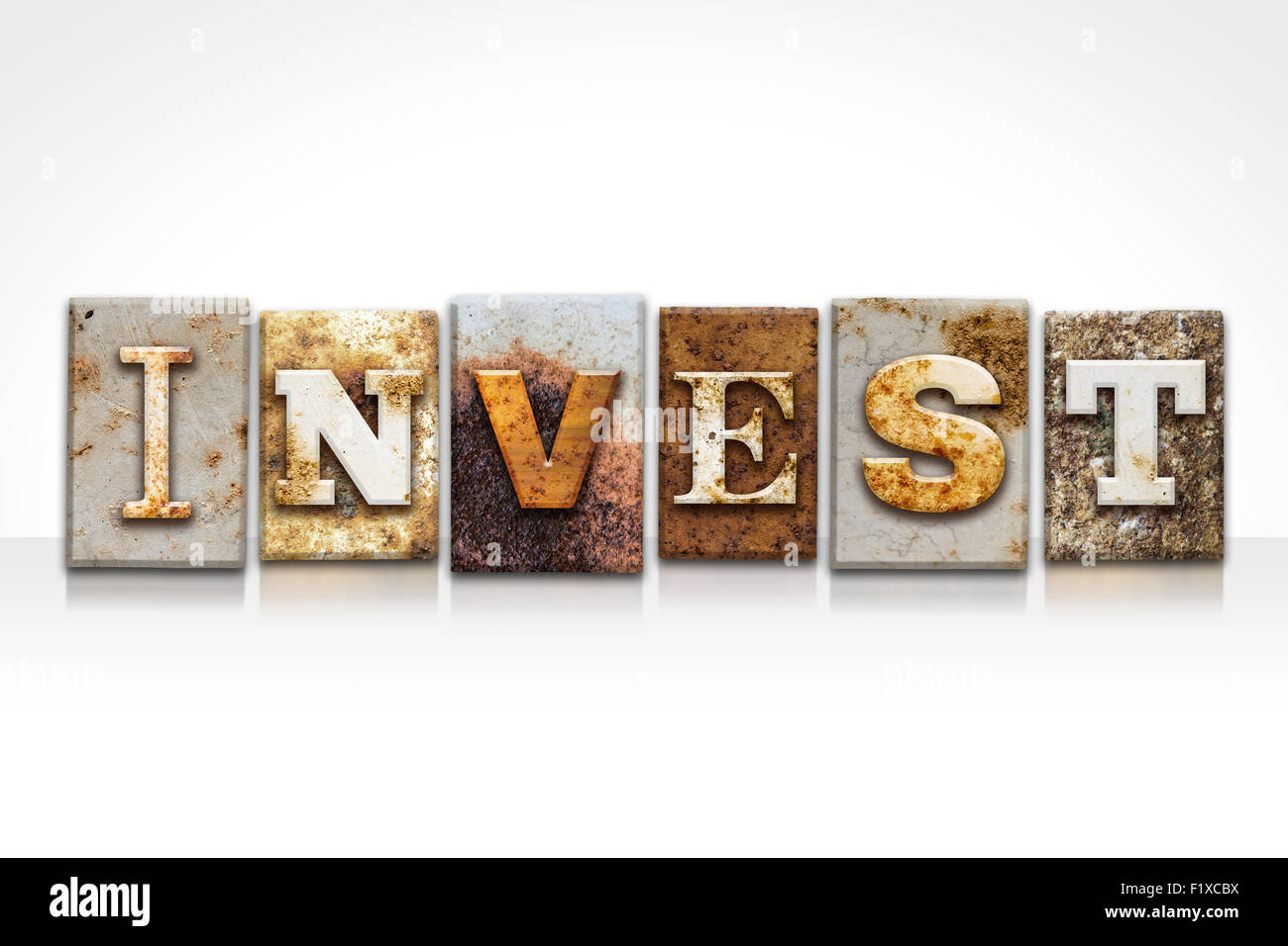 The word "INVEST" written in rusty metal letterpress type isolated on a ...