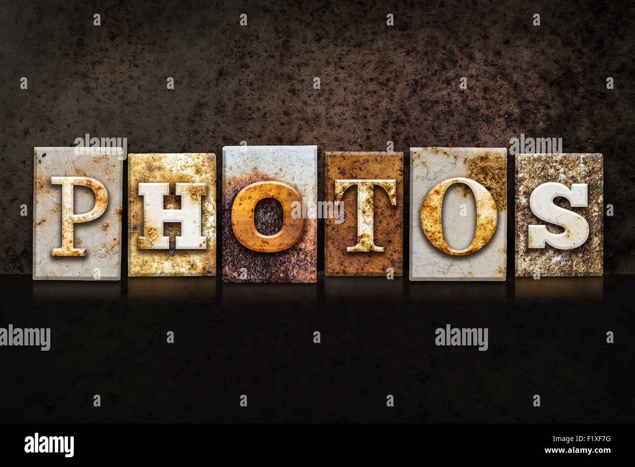 The word "PHOTOS" written in rusty metal letterpress type on a dark ...