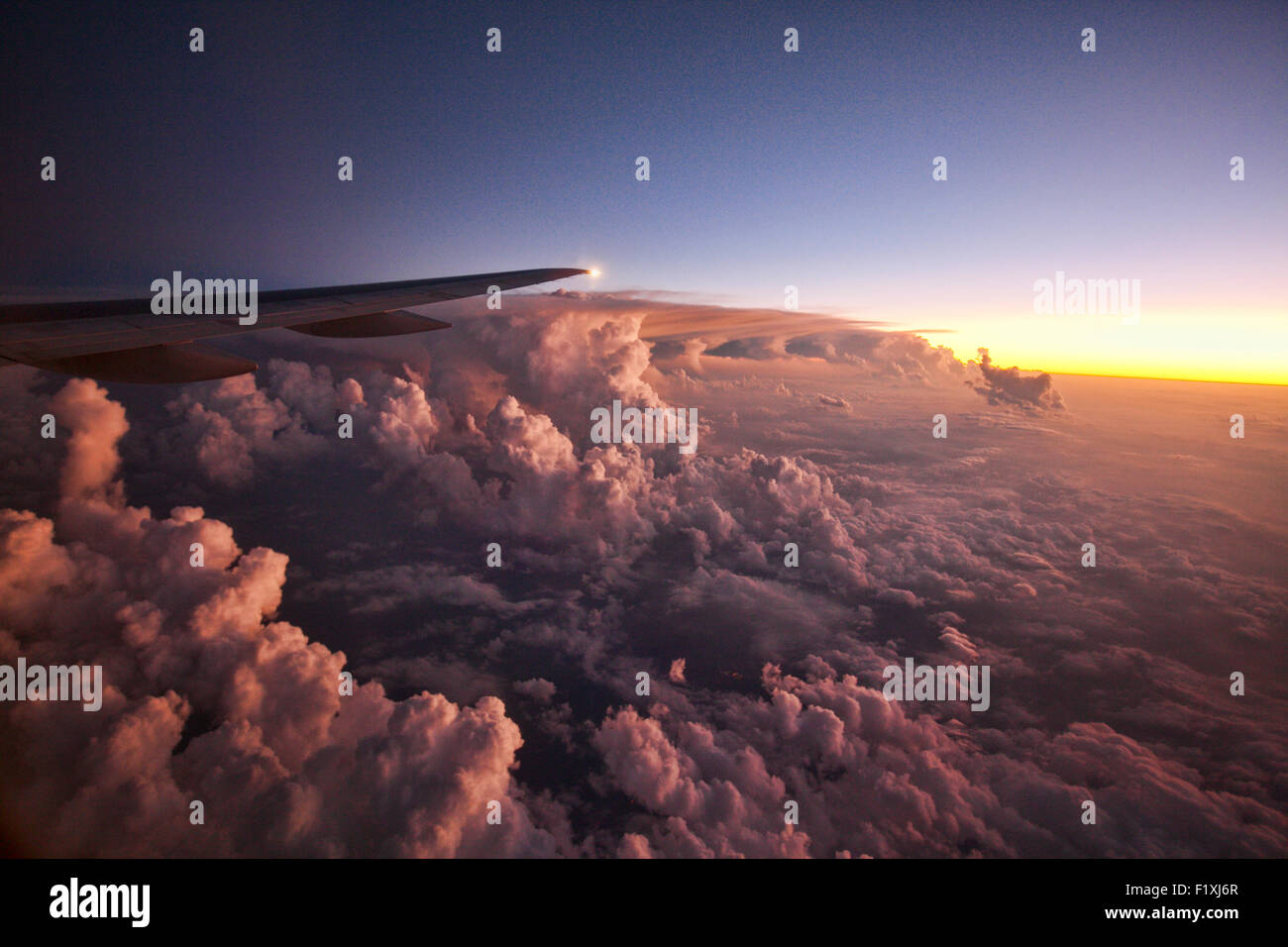 Looking out a plane window while flying over a storm at sunset Stock ...