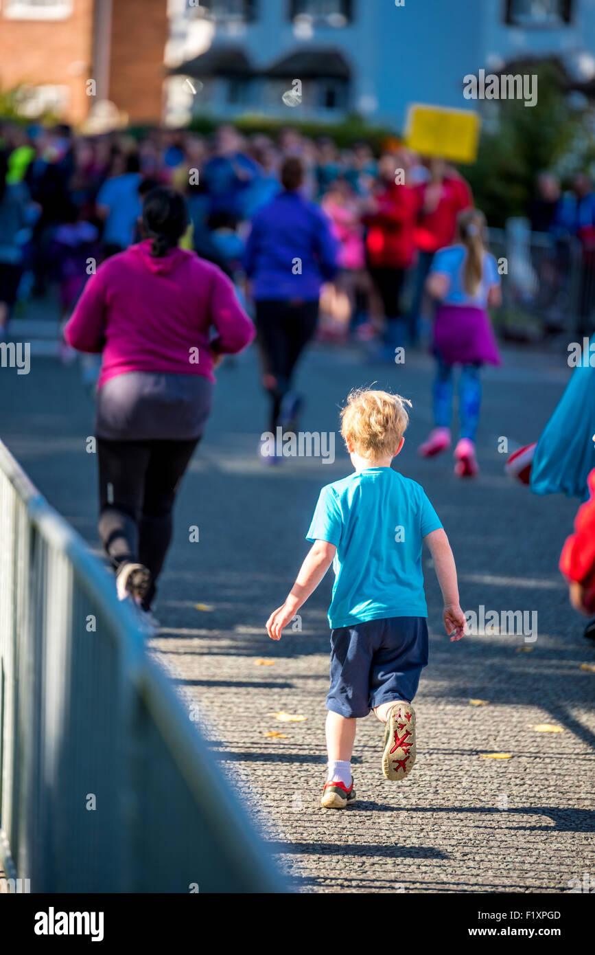 The back of a young boy in the sunlight running in the childrens fun ...