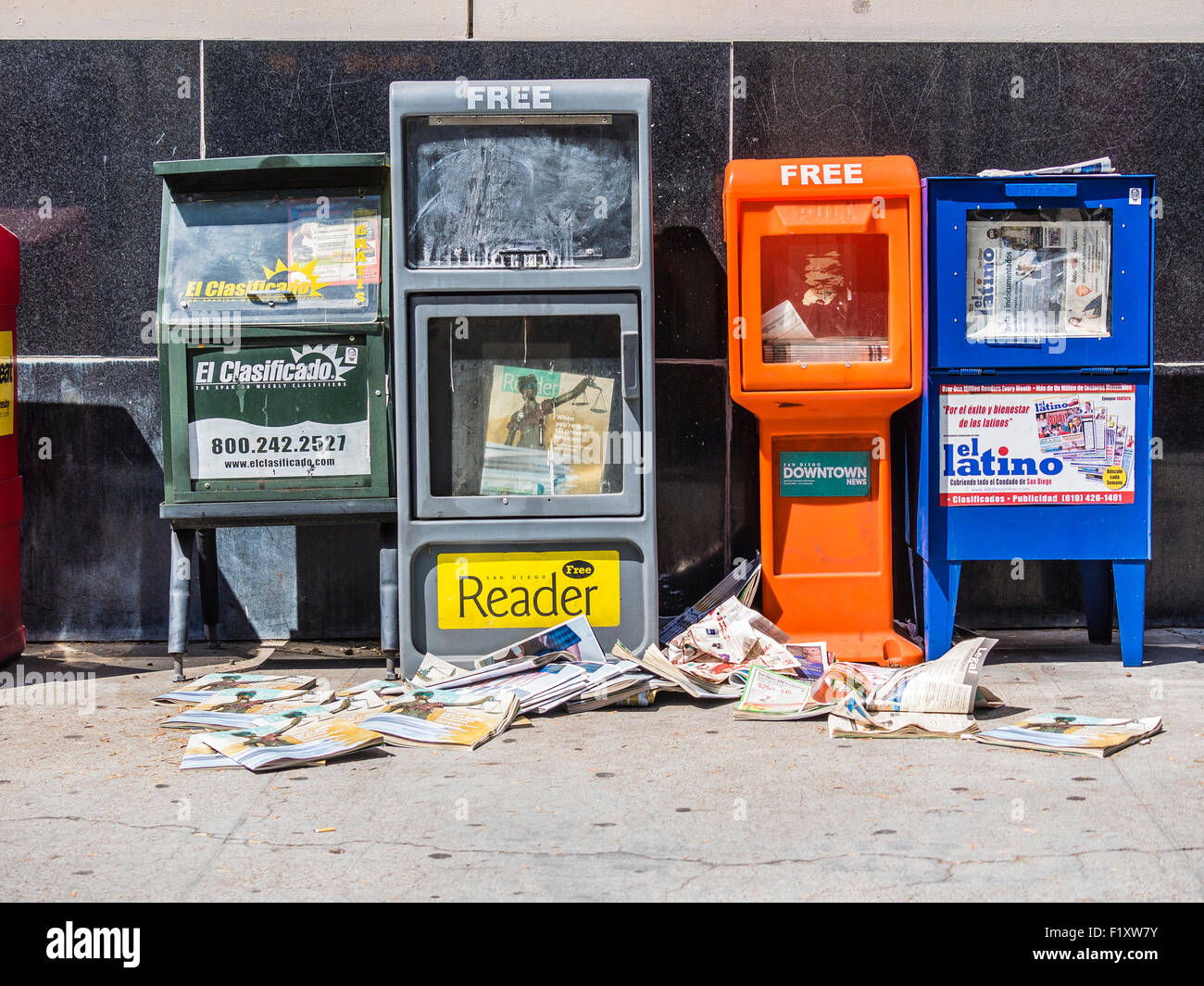 Newspaper stands with loose newspapers lying on the sidewalk creating a ...