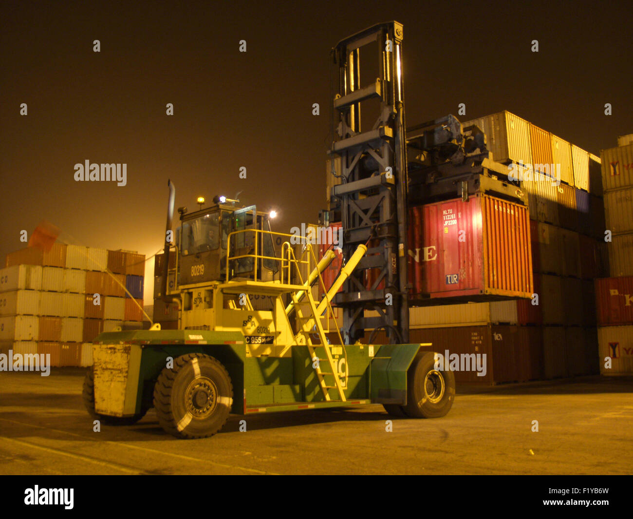 shipping container being handled by a spreader forklift at port ...