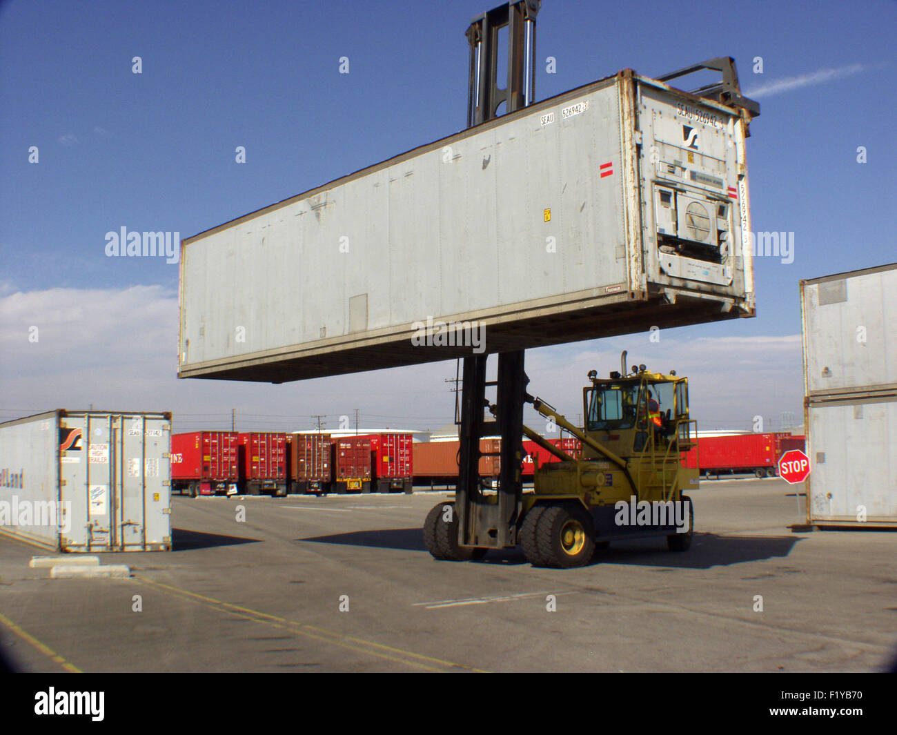 shipping container being handled by a spreader forklift at port ...