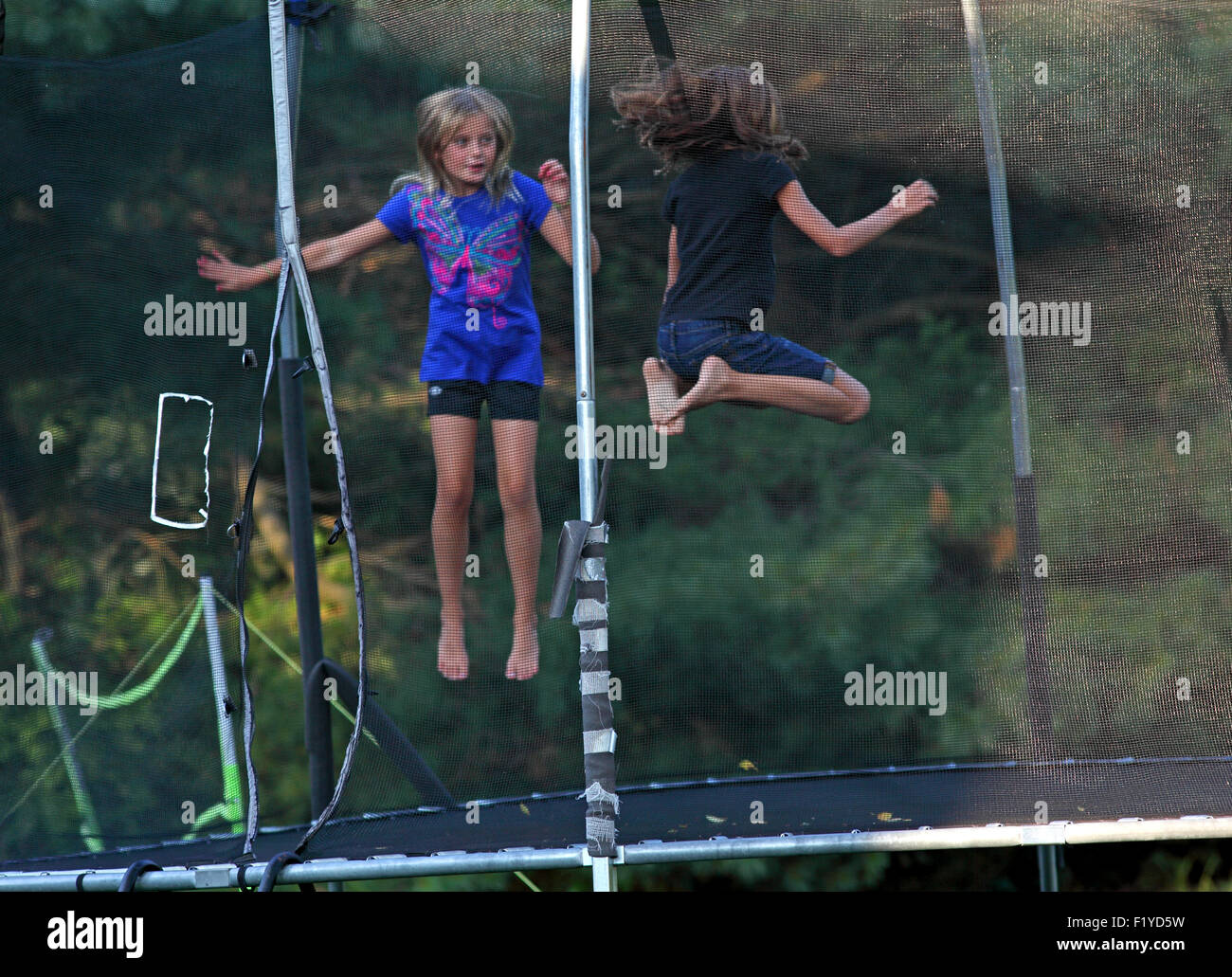 Two girls jumping on trampoline Stock Photo - Alamy
