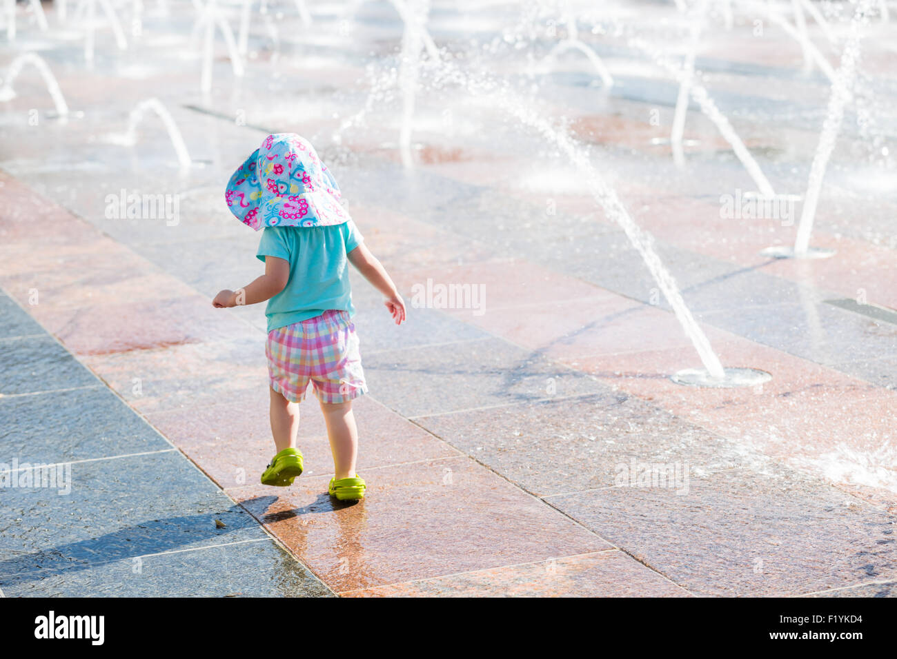Cute toddler girl playing with small fountains in splash park Stock ...