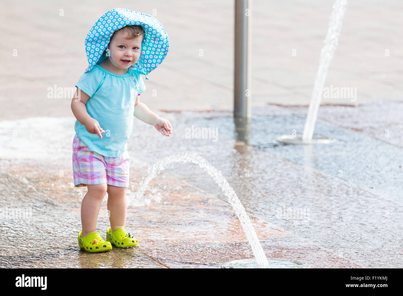 Cute toddler girl playing with small fountains in splash park Stock ...