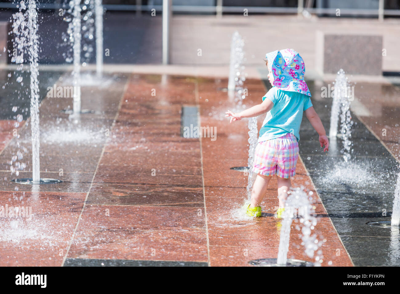 Cute toddler girl playing with small fountains in splash park Stock ...