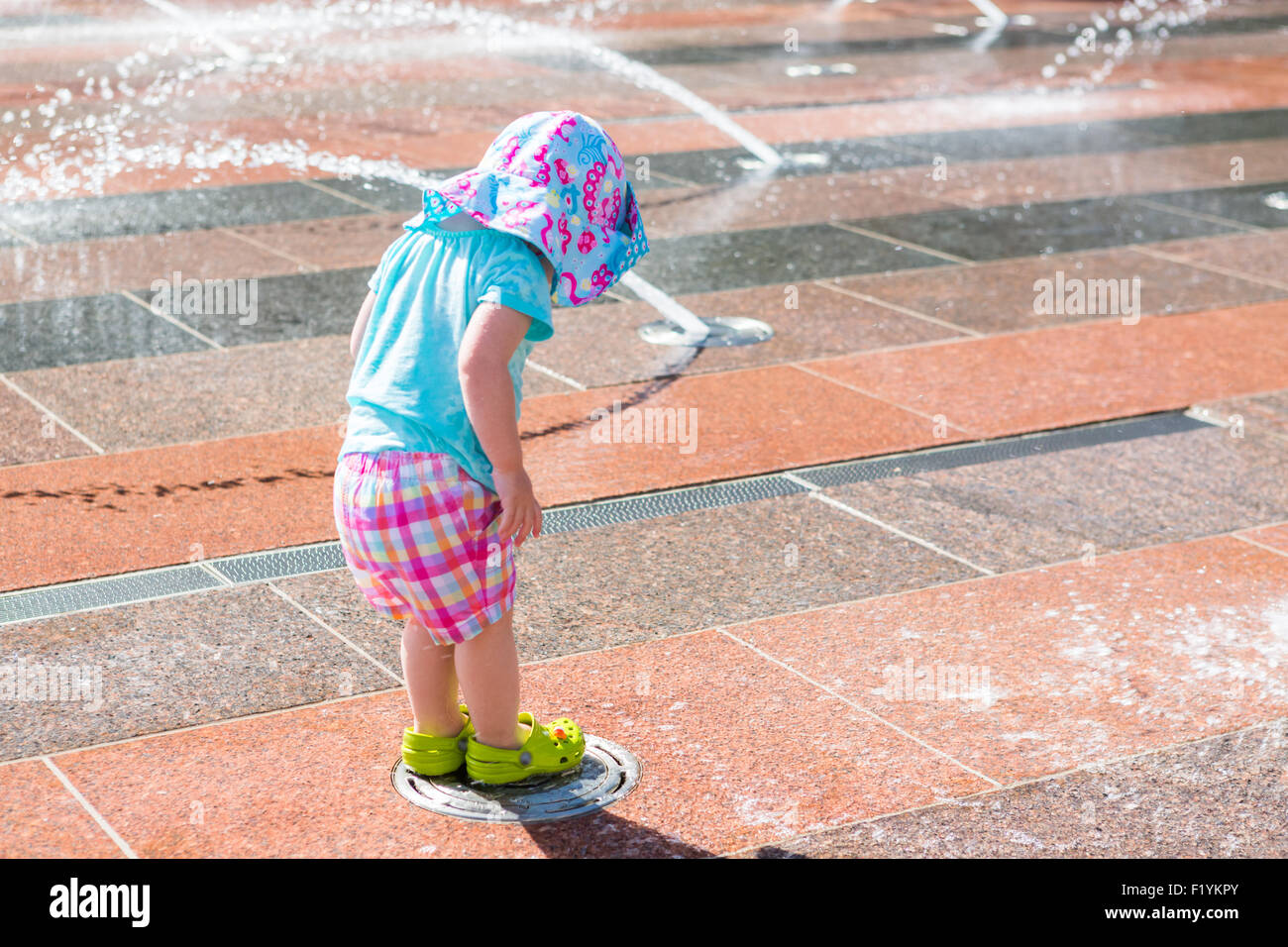 Cute toddler girl playing with small fountains in splash park Stock ...