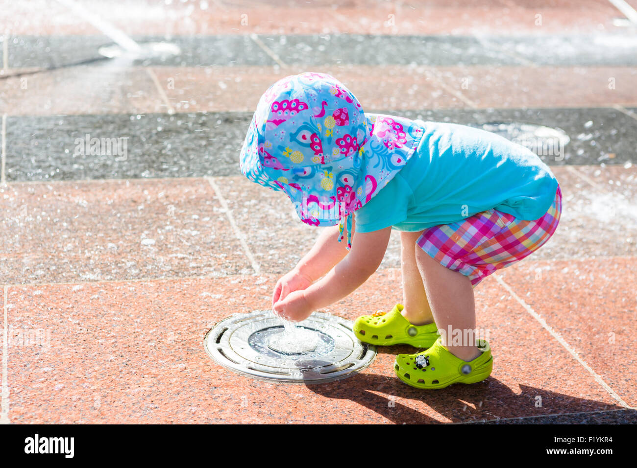 Cute toddler girl playing with small fountains in splash park Stock ...