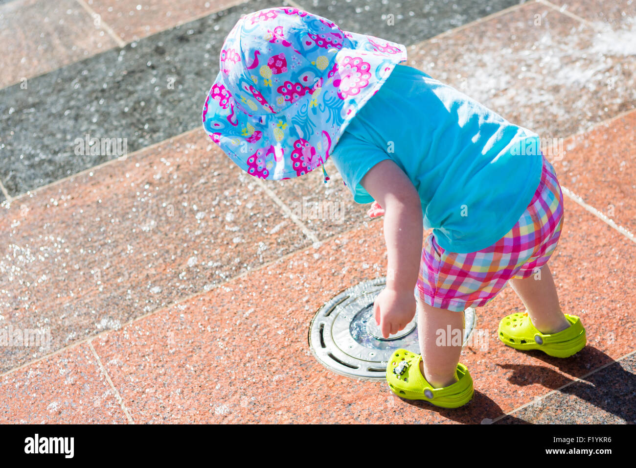 Cute toddler girl playing with small fountains in splash park Stock ...